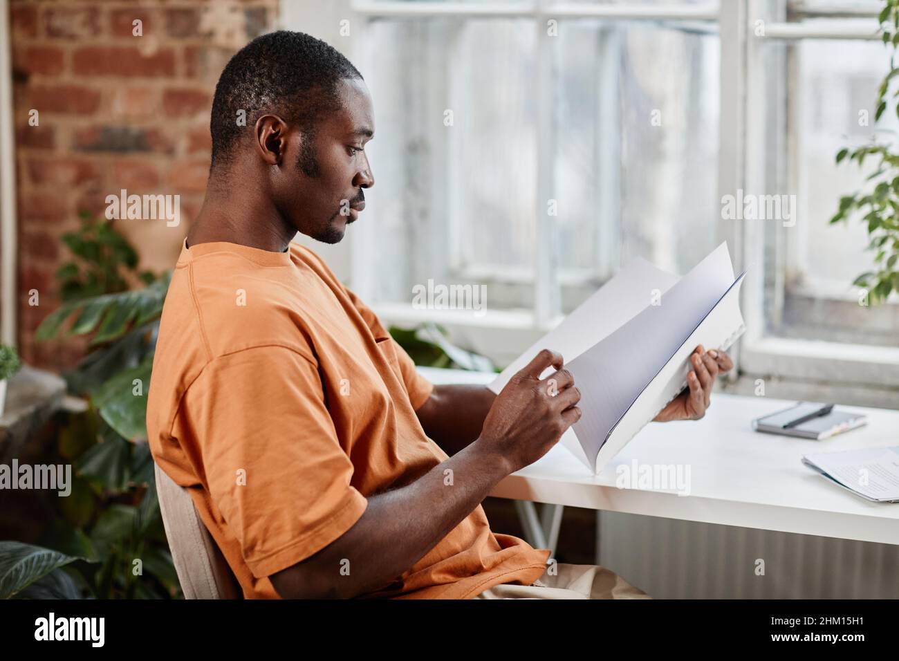 Side view of young African American businessman looking through ...