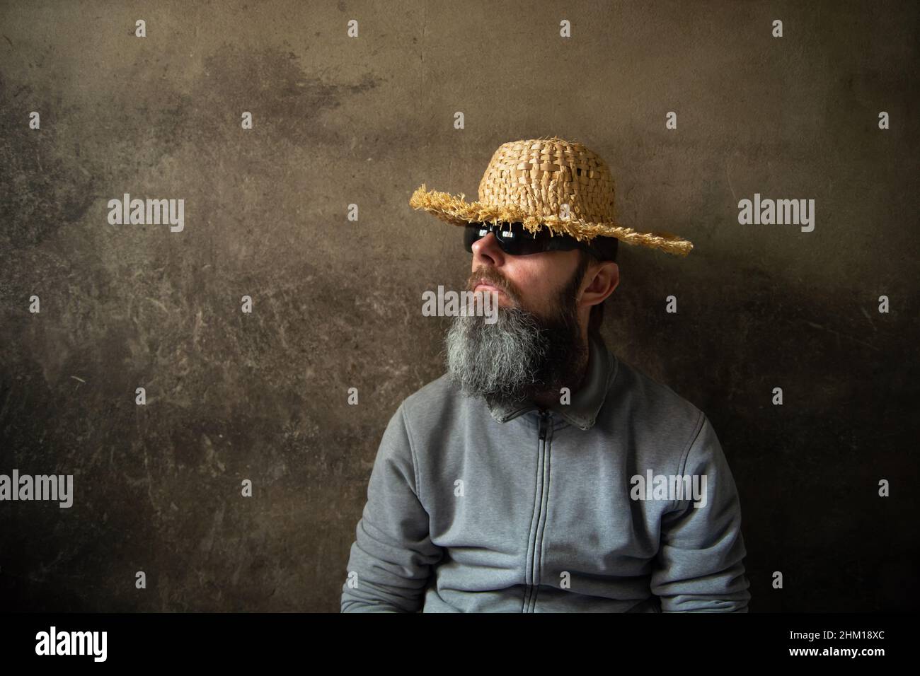 A man with a beard in a straw hat against a wall background Stock Photo ...