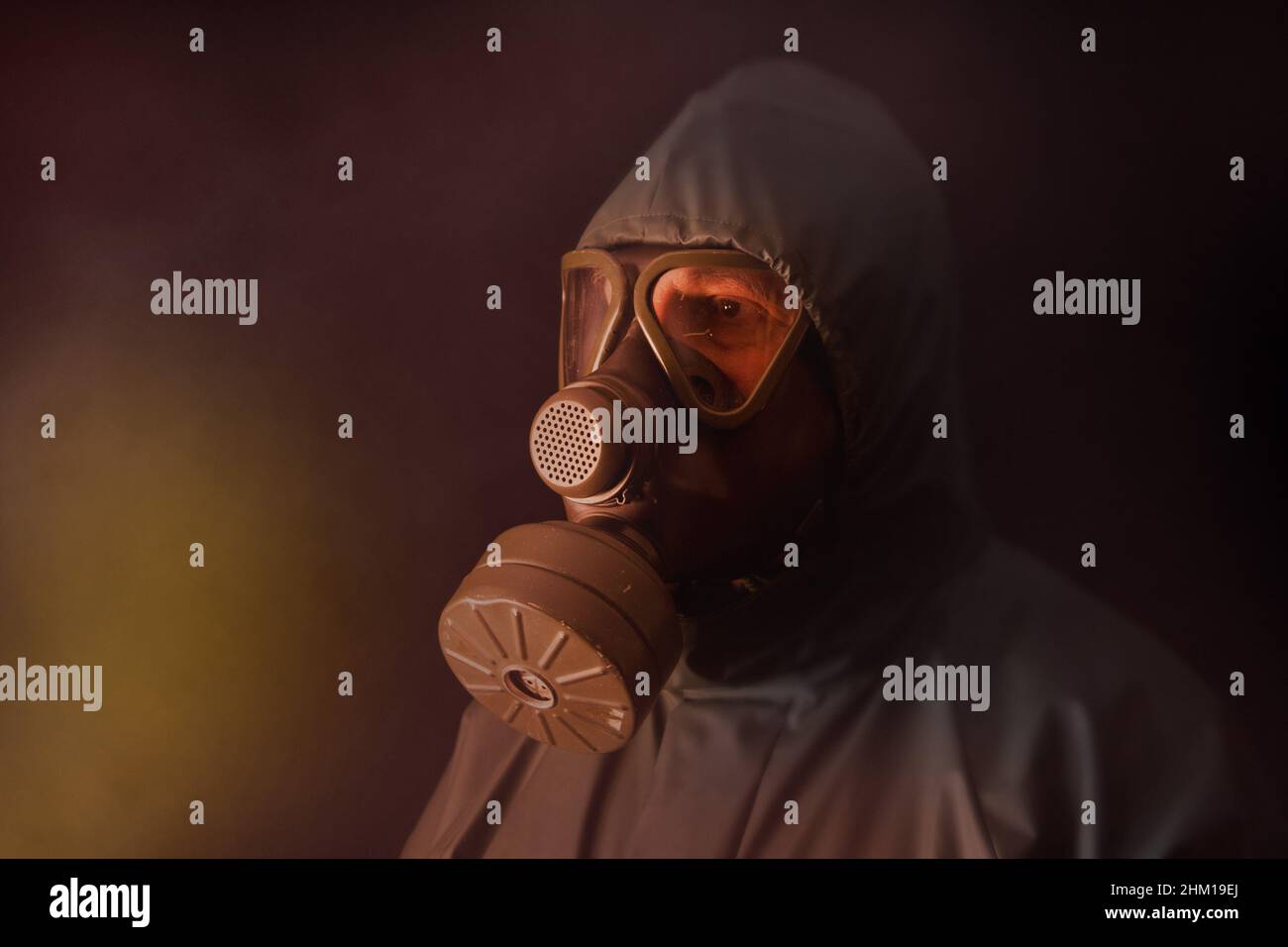 A man with a gas mask and protective suit stands in the smoke, which is ...