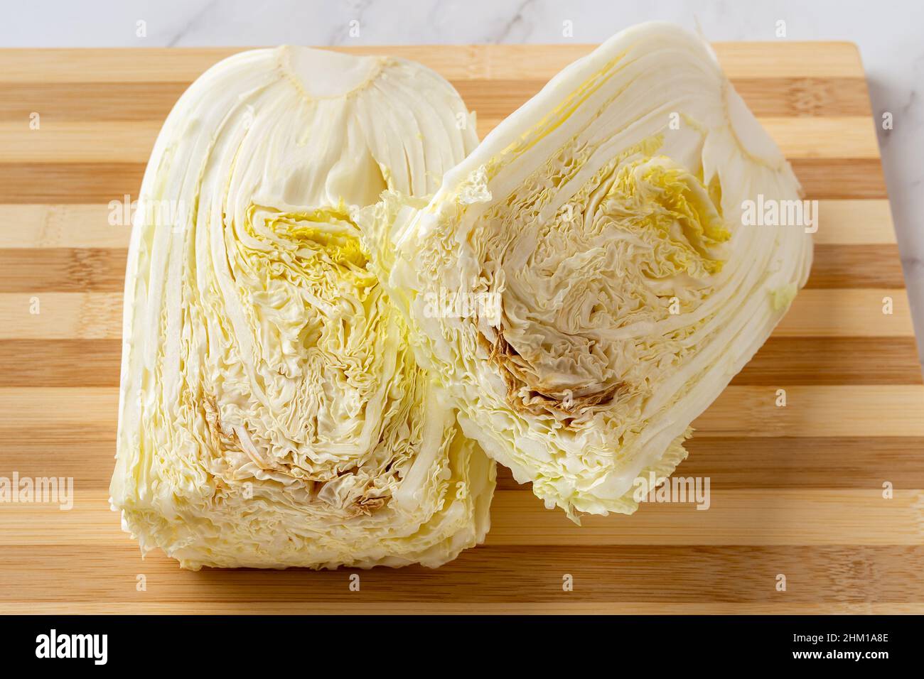 Rotten napa cabbage cut in half on a chopping board. The cabbagehead ...