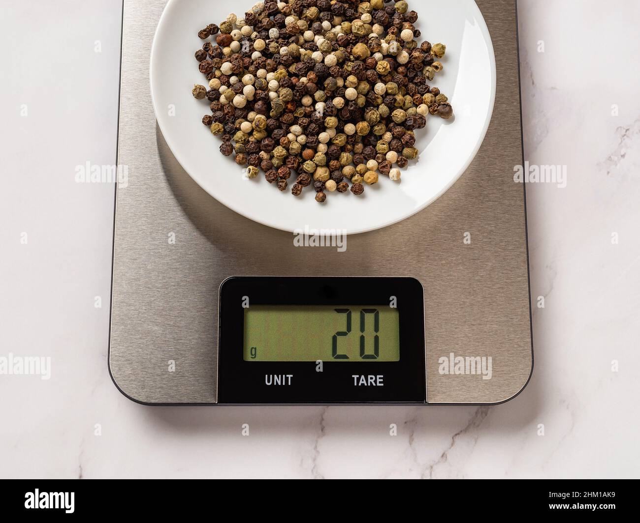 Pepper spice on a sauser over digital kitchen scales. Scales displaying ...