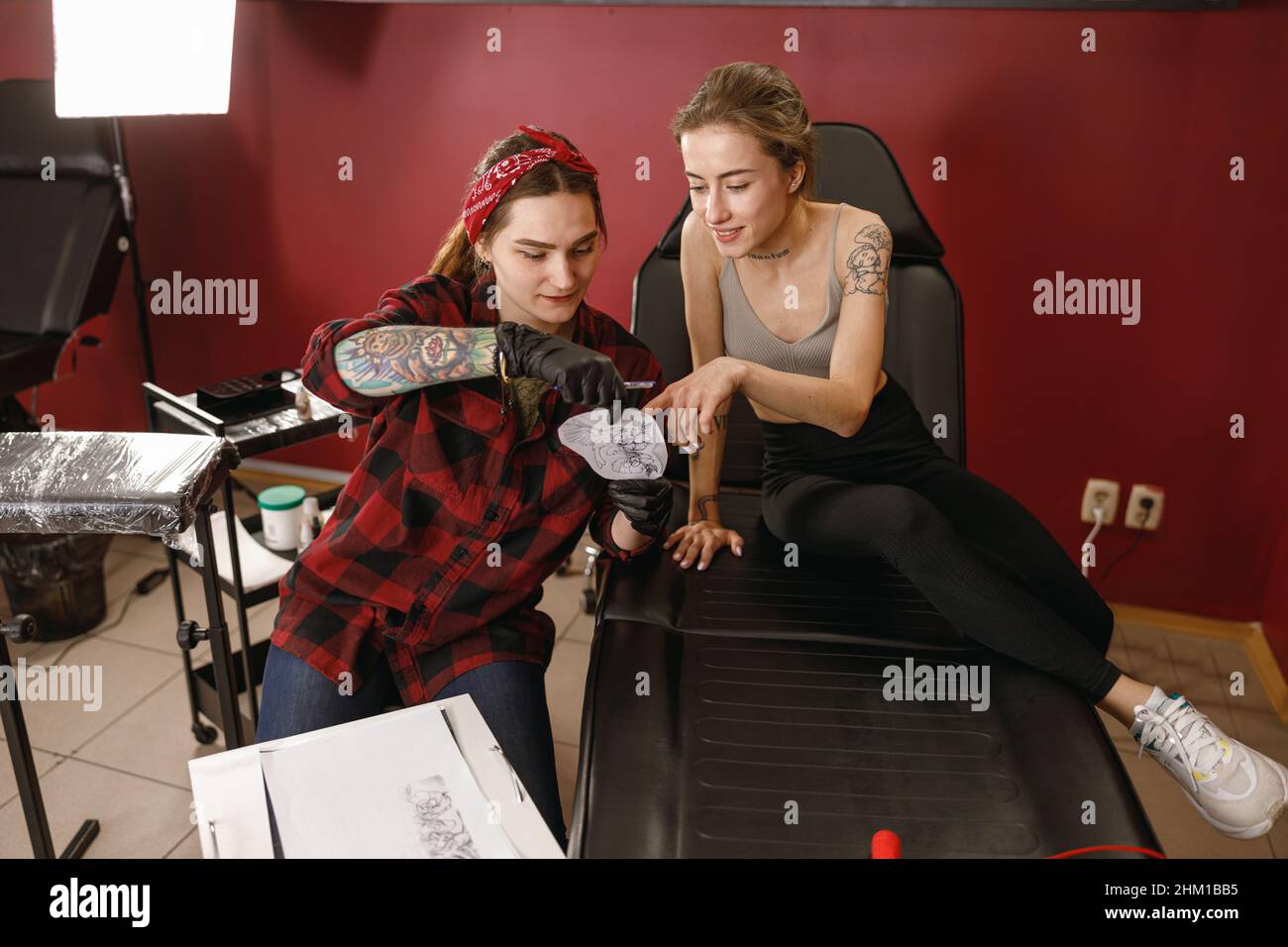 Tattoo artist showing the client drawing for tattoo Stock Photo - Alamy