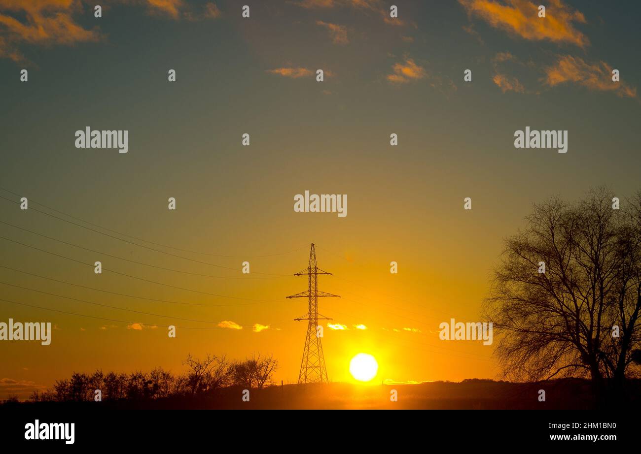 Power transmission towers or electricity pylons with golden sky and ...
