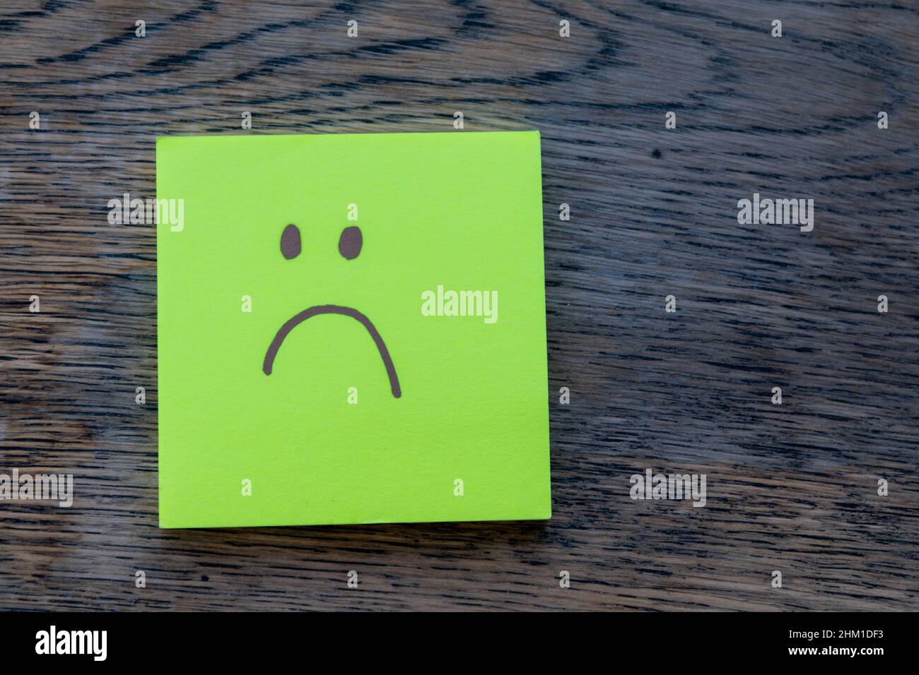 Sad face hand drawn on post-it note, isolated on rustic wooden ...
