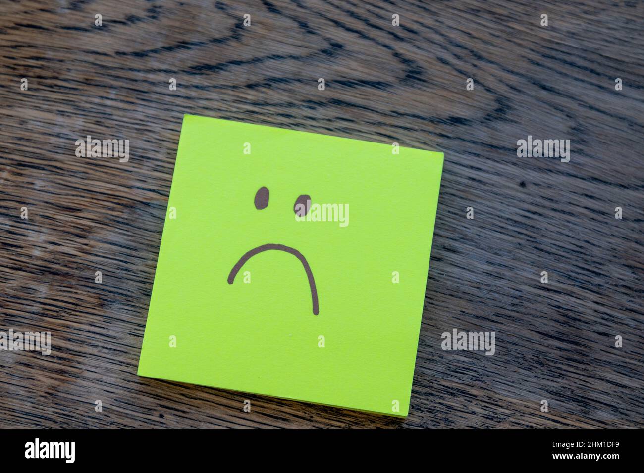 Sad face hand drawn on post-it note, isolated on rustic wooden ...