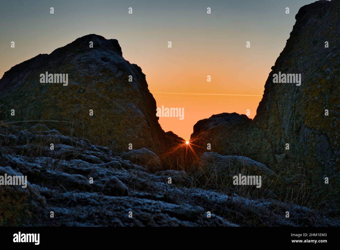 Sun peaking between two rocks at winter solstice Stock Photo - Alamy