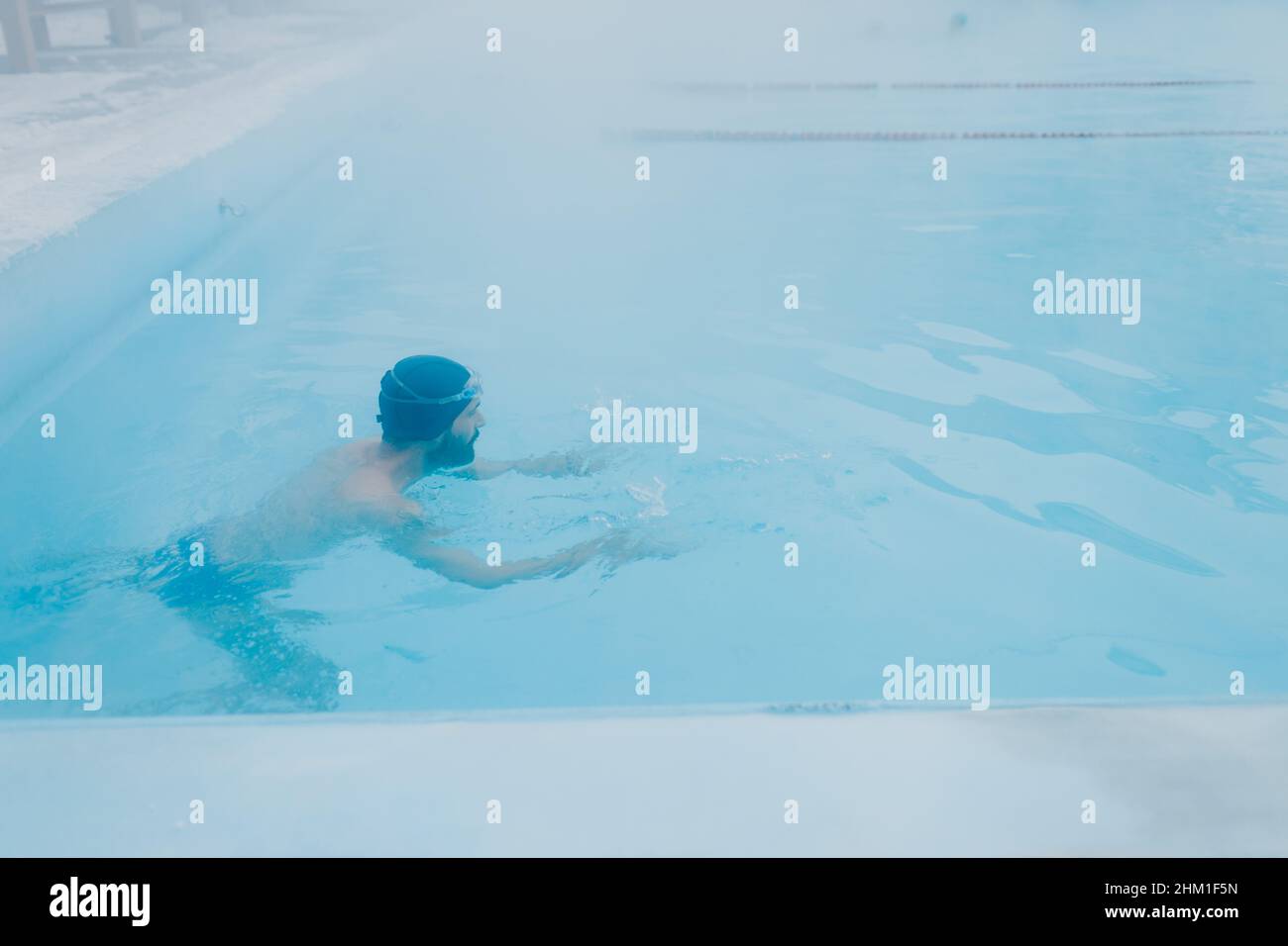 Fit swimmer male training swim in open winter swimming pool with fog ...