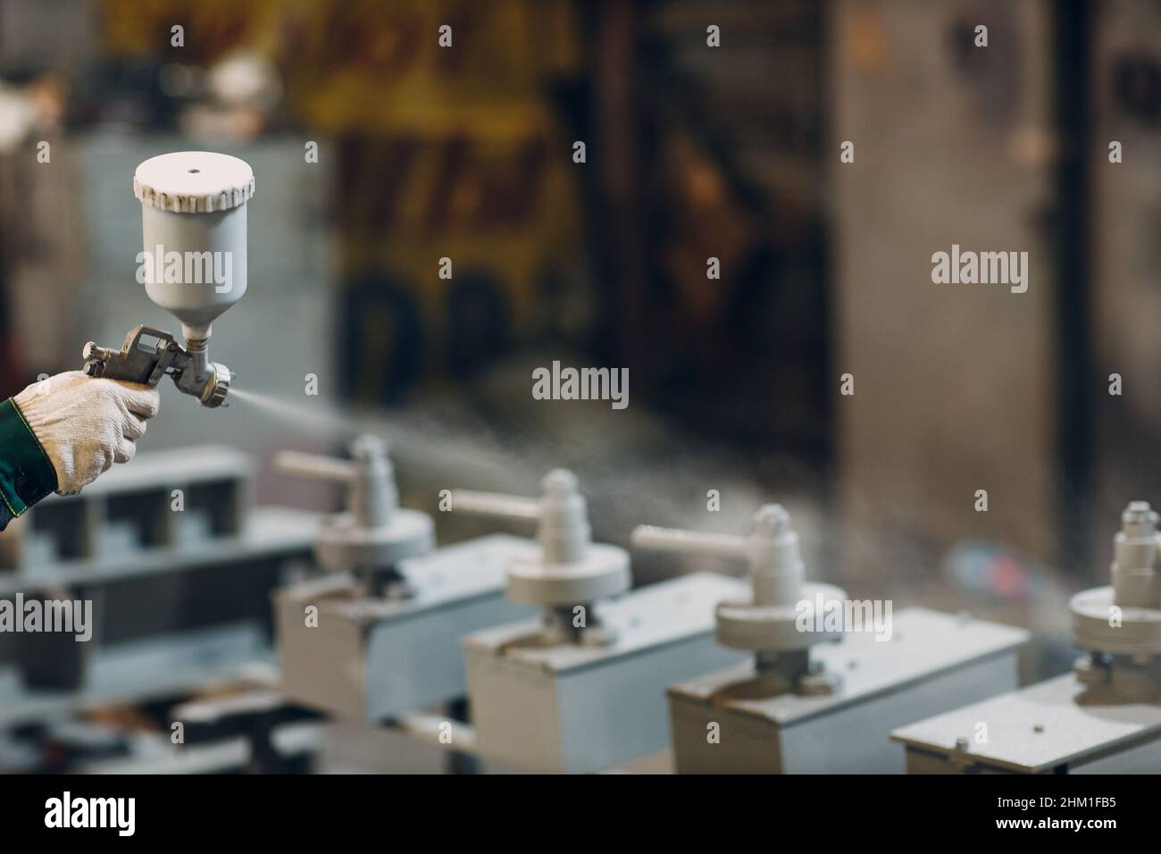Powder primer coating of metal parts. Worker man in a protective suit ...