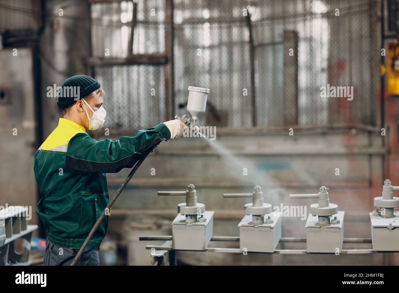 Powder primer coating of metal parts. Worker man in a protective suit ...