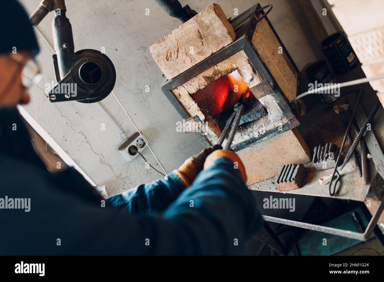 Blacksmith forge oven with hot flame. Smith put in and heating iron ...