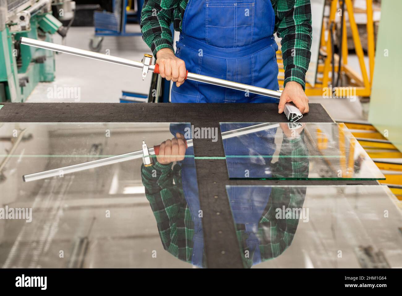 Glazier standing over a cut glass pane with specialized cutting ...