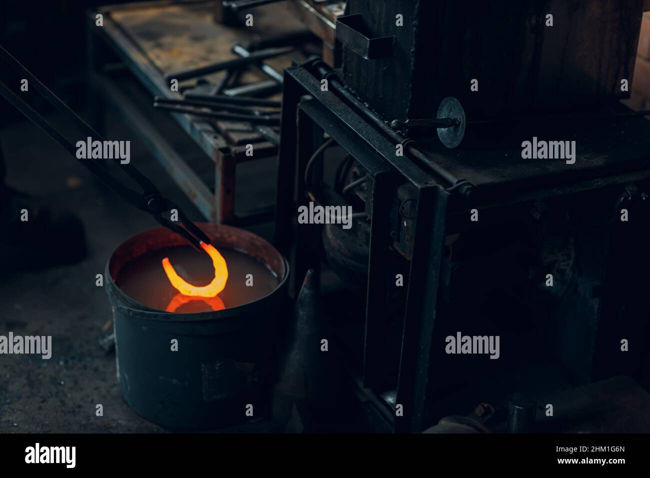 Blacksmith forges and tempering metal horseshoe in jar with water at ...