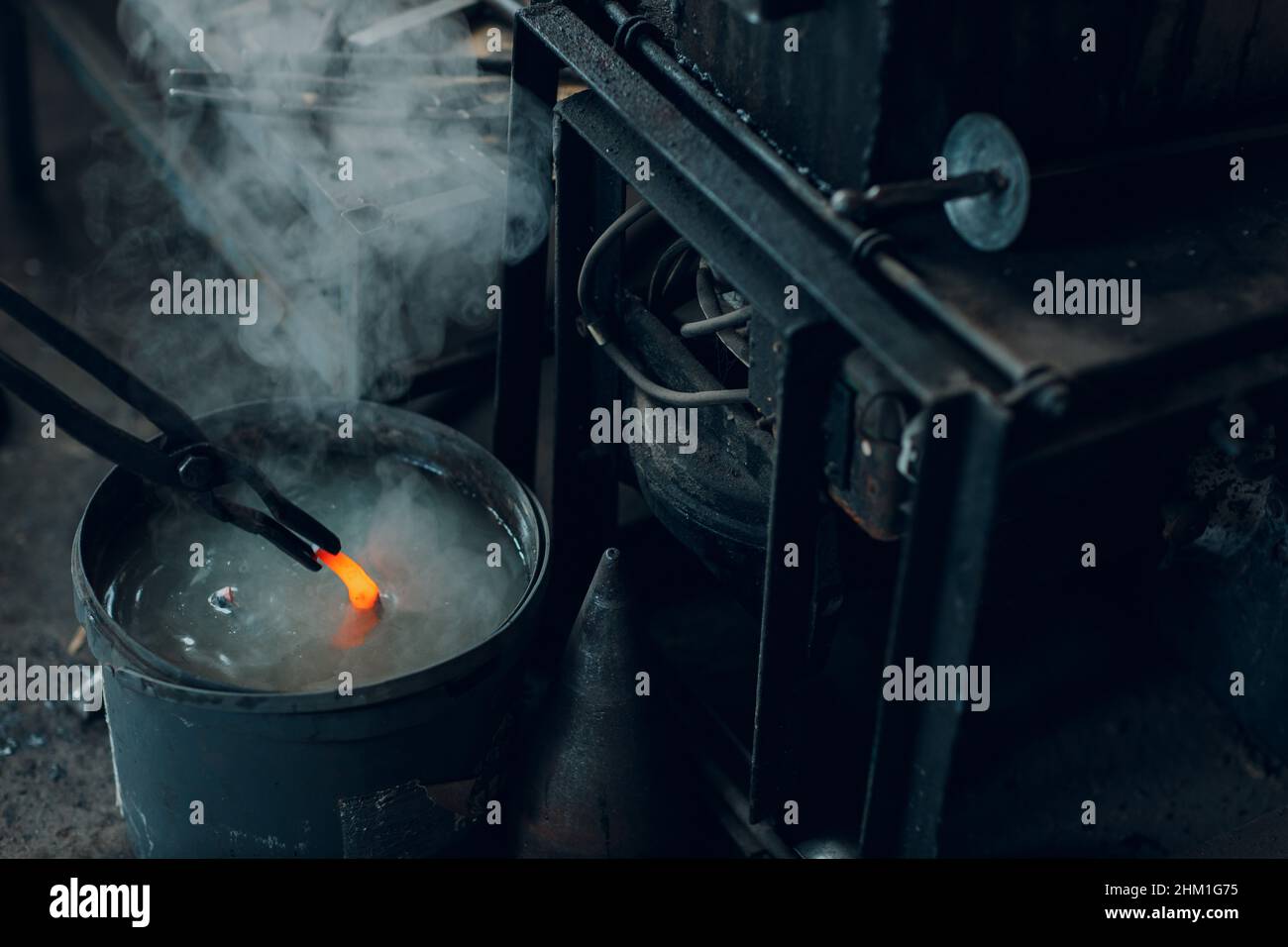 Blacksmith forges and tempering metal horseshoe in jar with water at ...