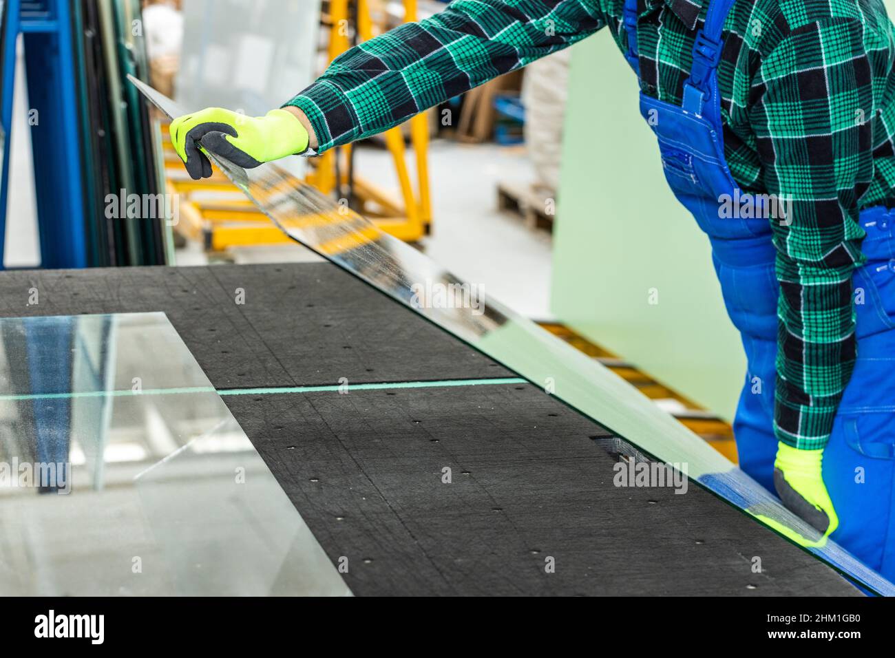The glazier places a pane of glass on a specialized table, Work in a ...