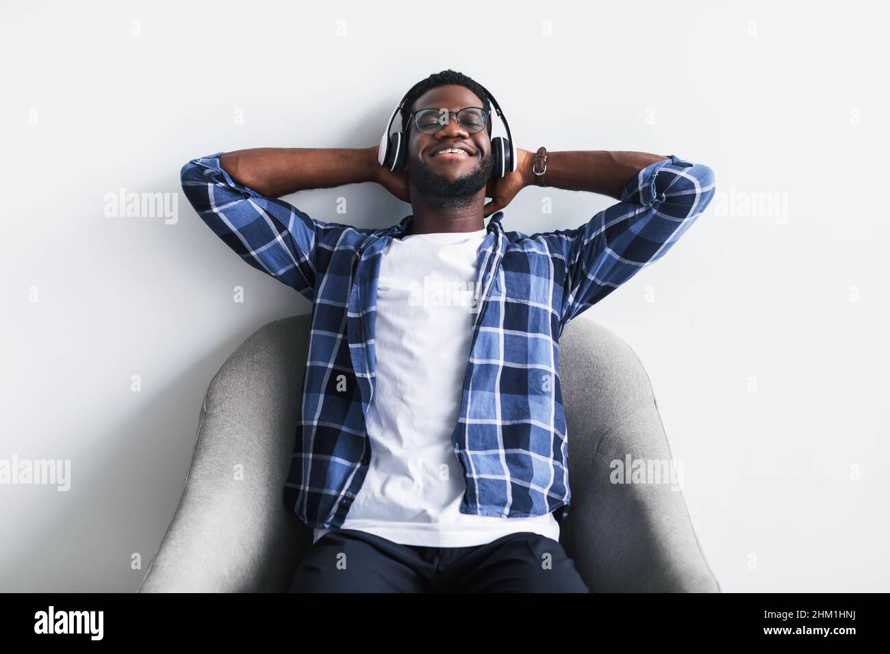 Relaxed African American guy listening to music in wireless headphones ...