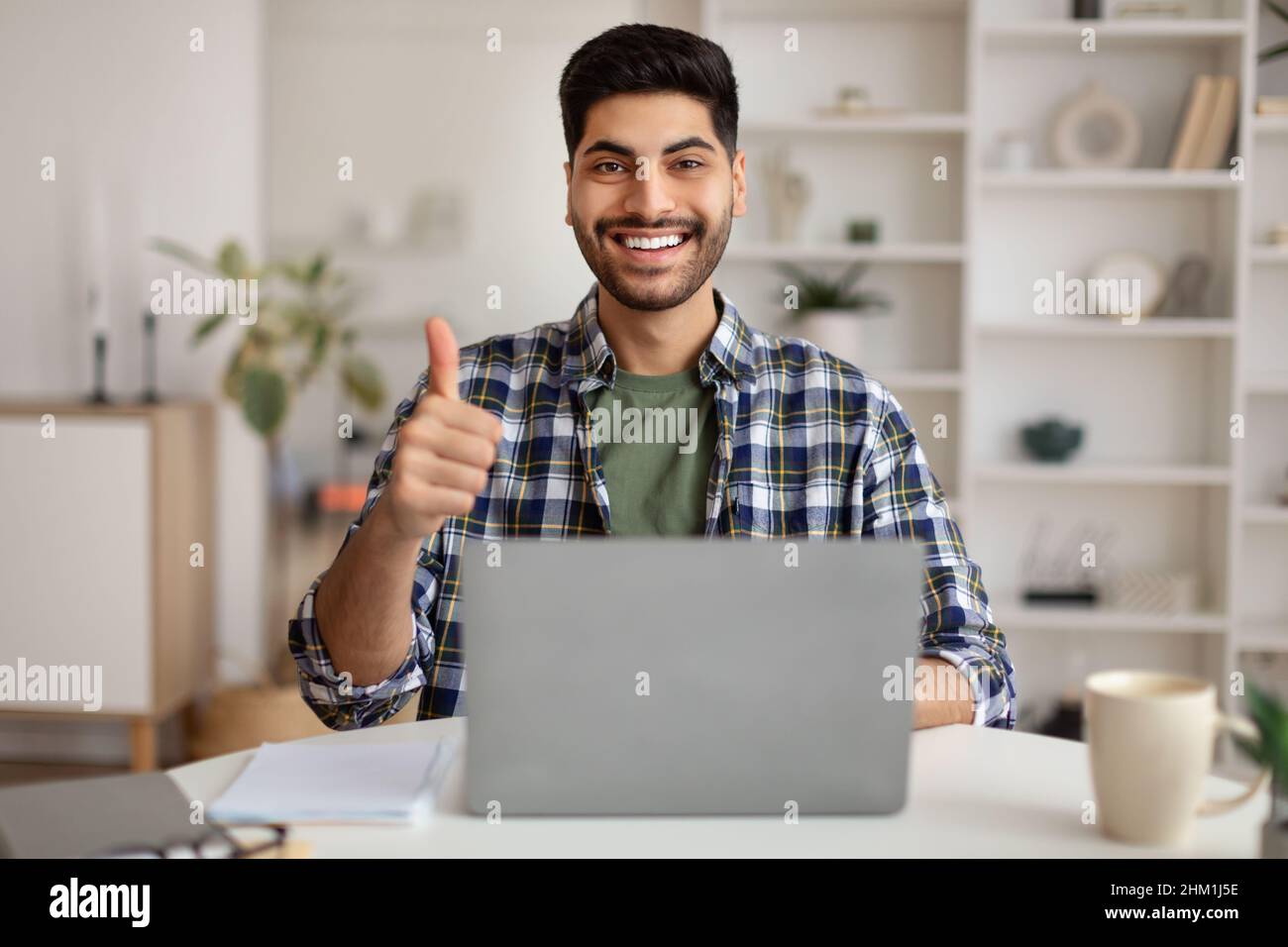 Portrait of smiling Arab man using laptop showing thumbs up Stock Photo ...