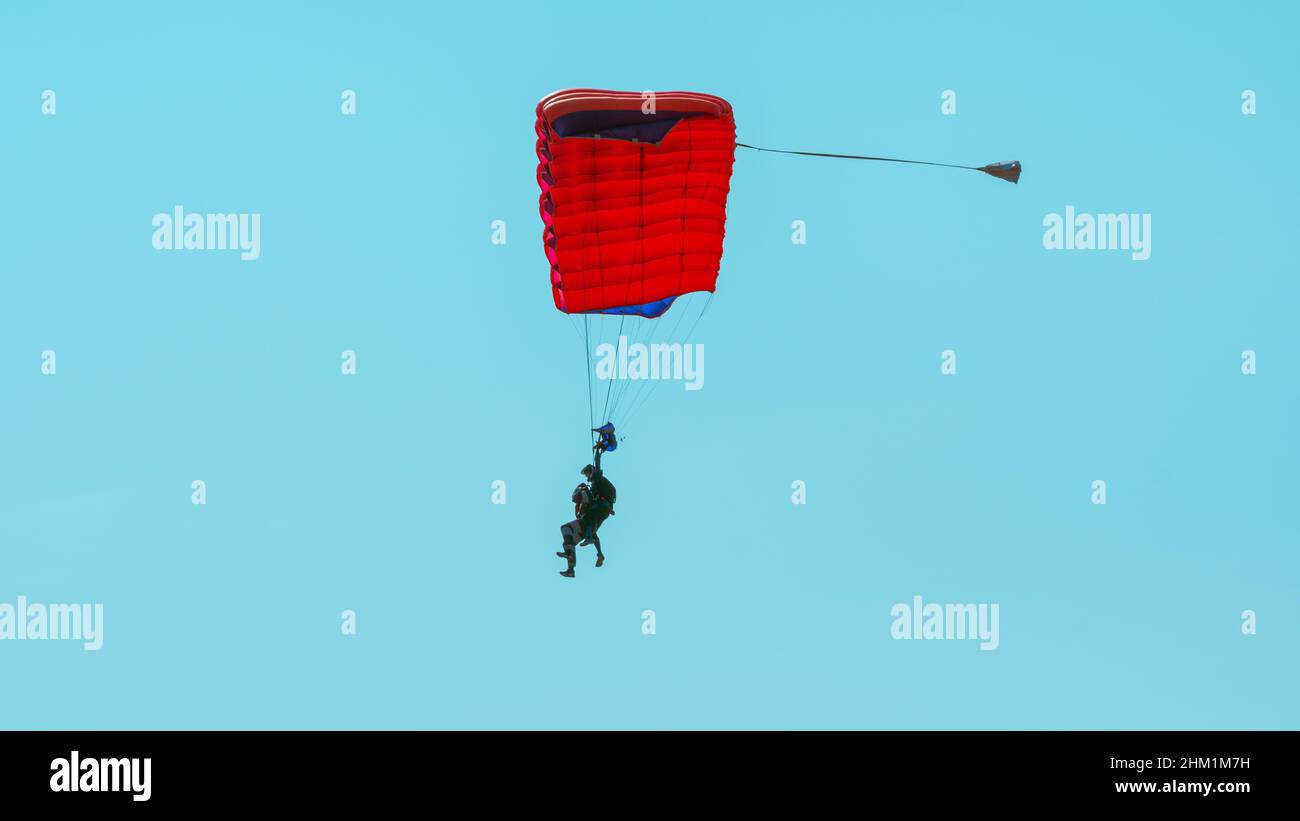 Tandem parachute jump. Silhouette of skydiver flying in blue clear sky ...