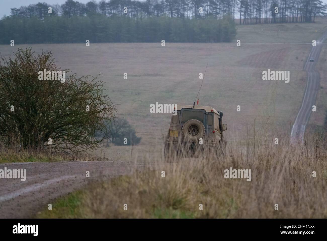 land rover defender 90 swb driving along an unmade stone track road ...