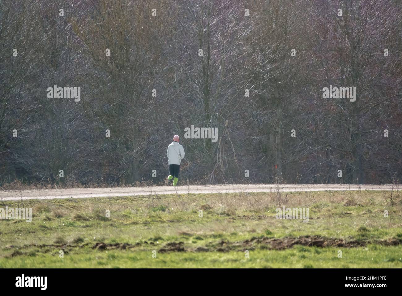 man wearing high visibility socks jogging on an unmade track road Stock ...