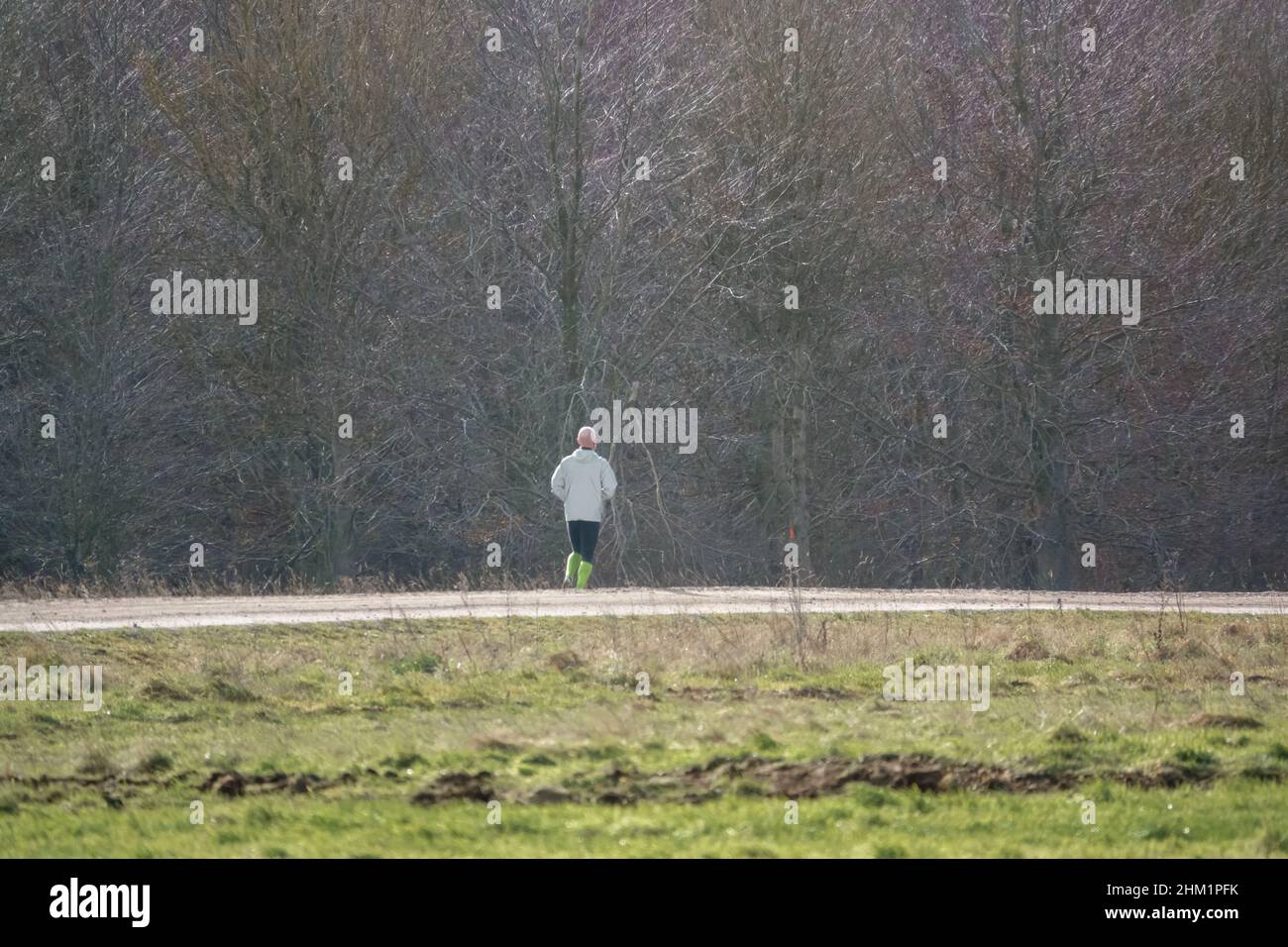 man wearing high visibility socks jogging on an unmade track road Stock ...