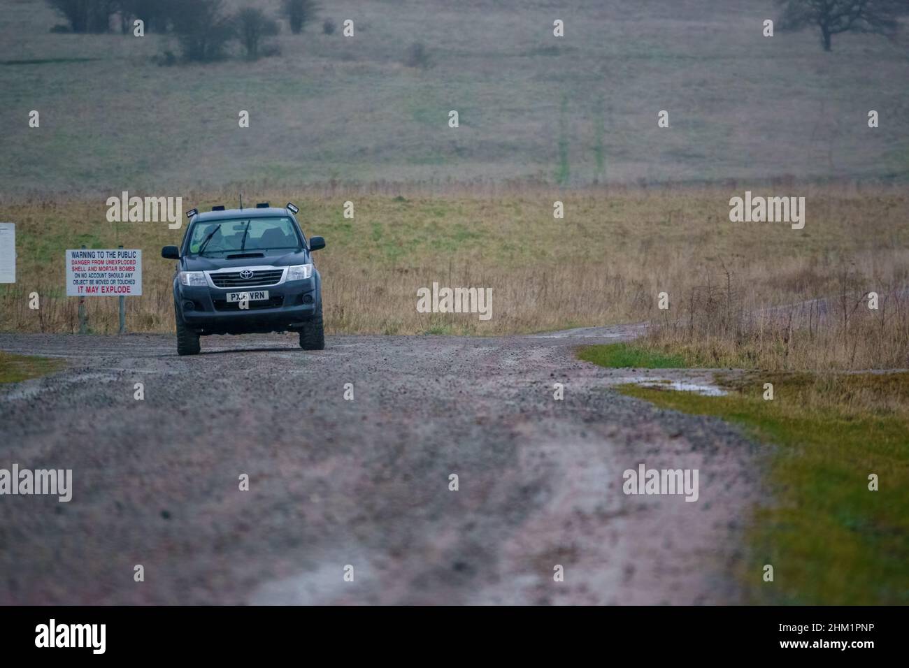 black toyota hilux SUV car driving along an unmade stone track road ...
