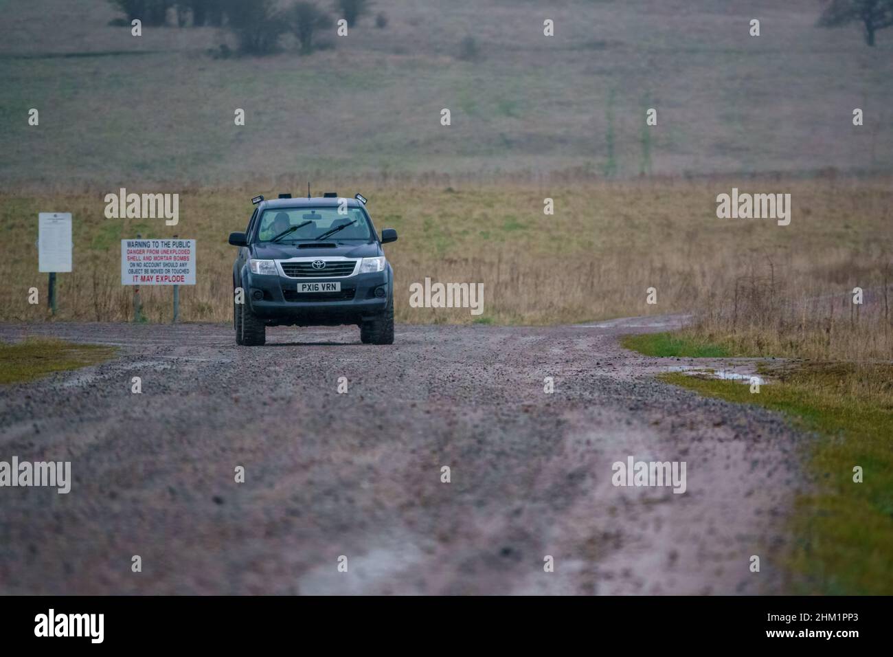 black toyota hilux SUV car driving along an unmade stone track road ...