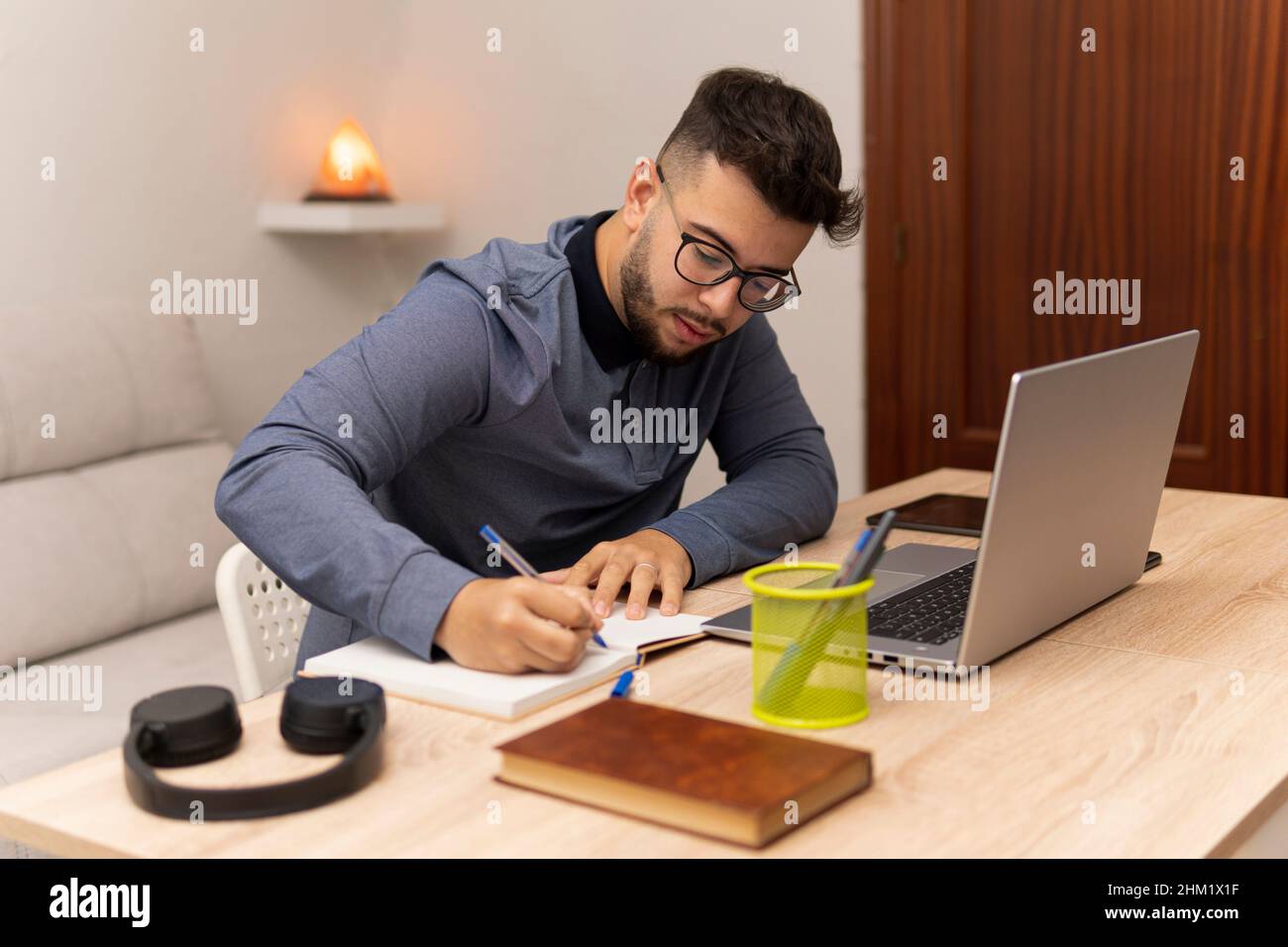 Young Latino boy writing his homework in his online college class with ...