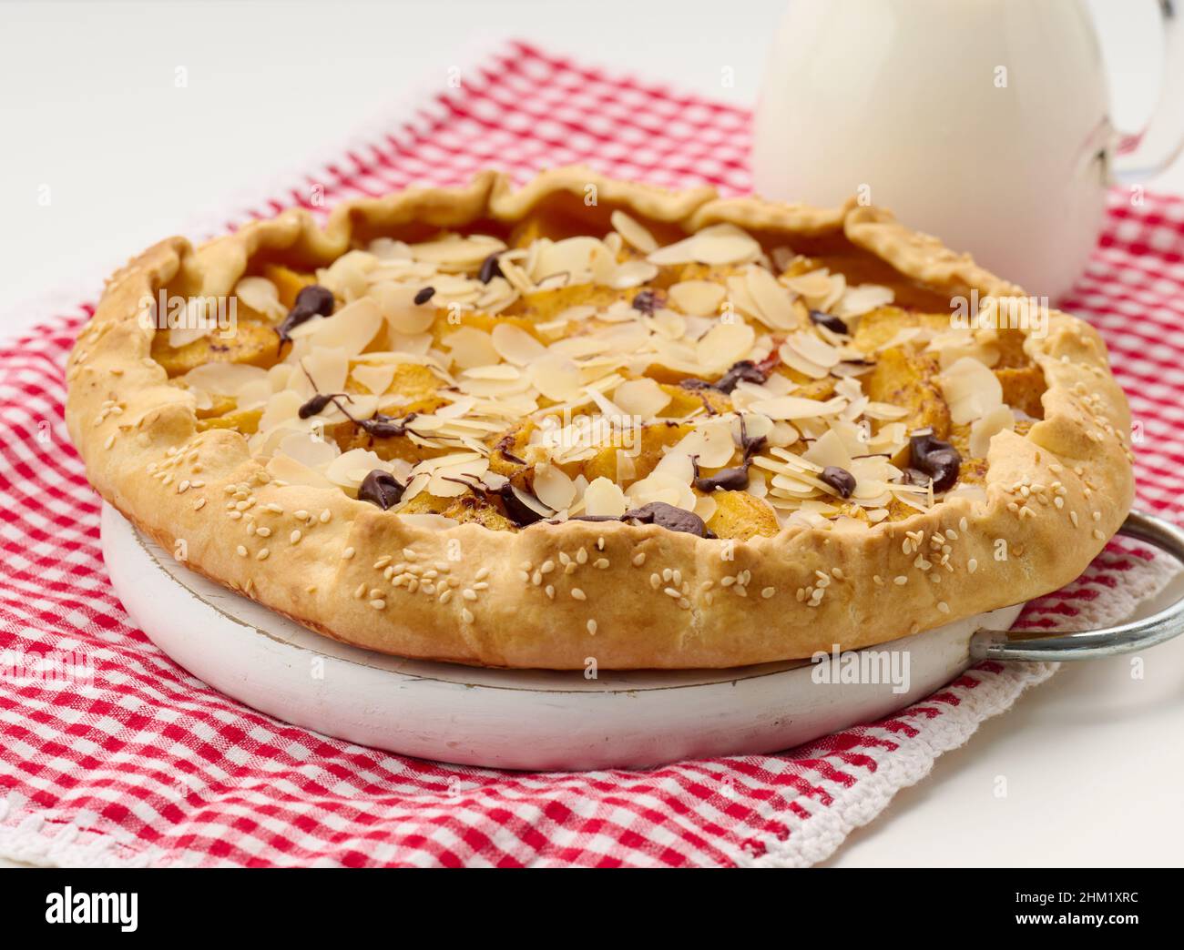 baked round pie with apple pieces, sprinkled with almond flakes on a ...