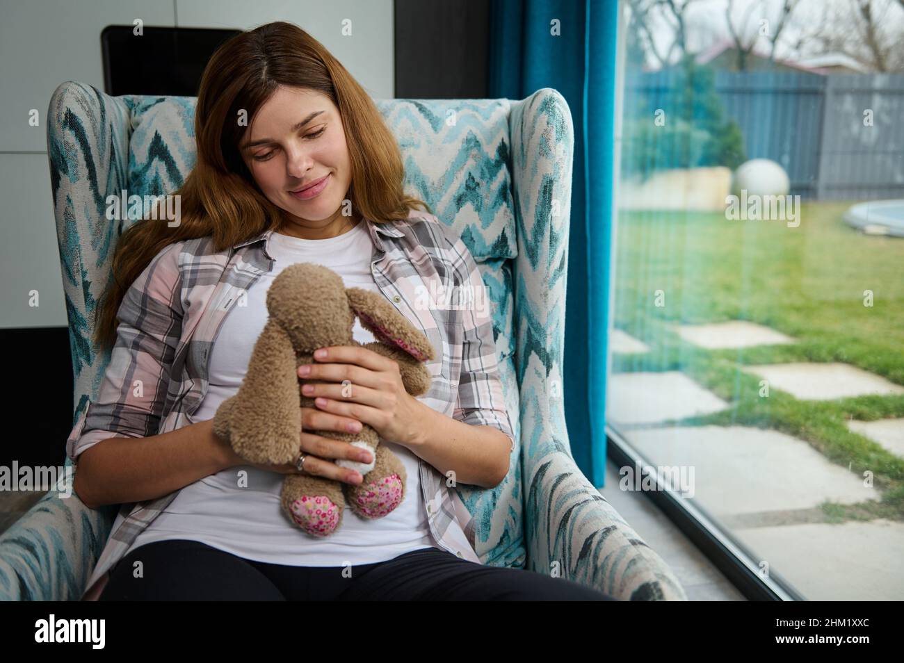 Beautiful serene pretty pregnant woman relaxing on an armchair, gently ...
