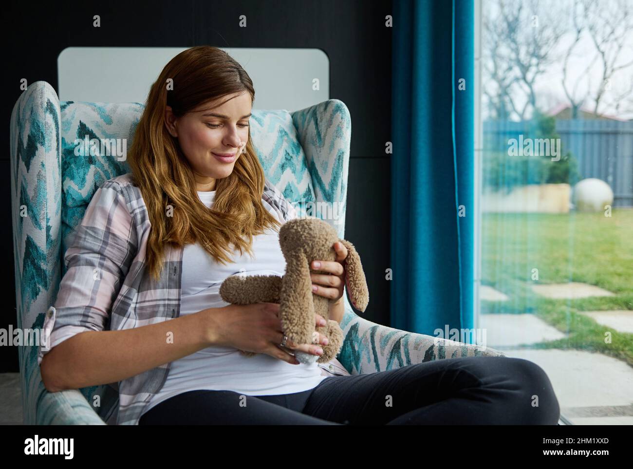Charming pregnant woman, expecting a baby, relaxing on an armchair near ...