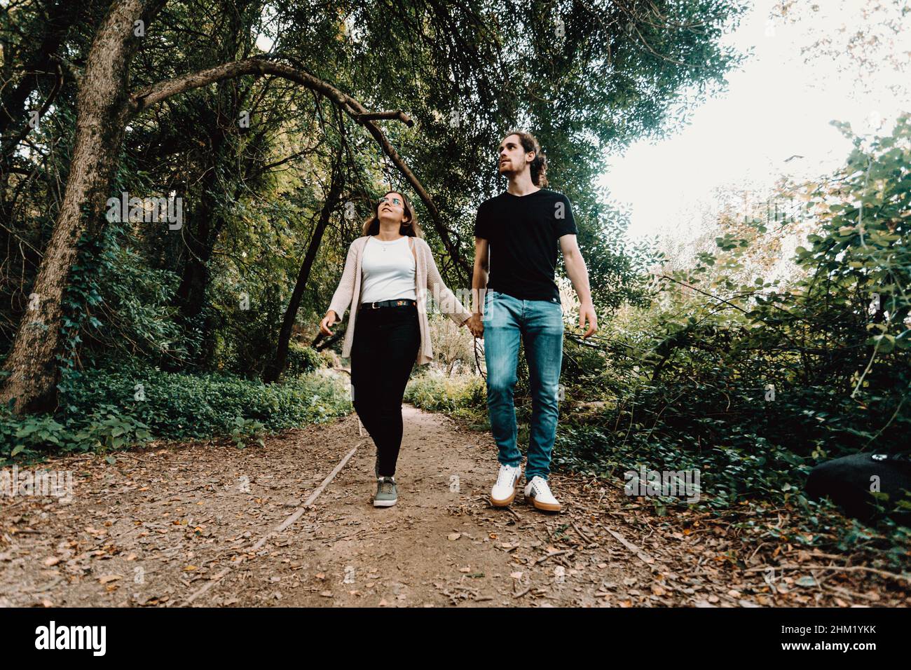 A front view of a young couple taking a walk and exploring the forest ...