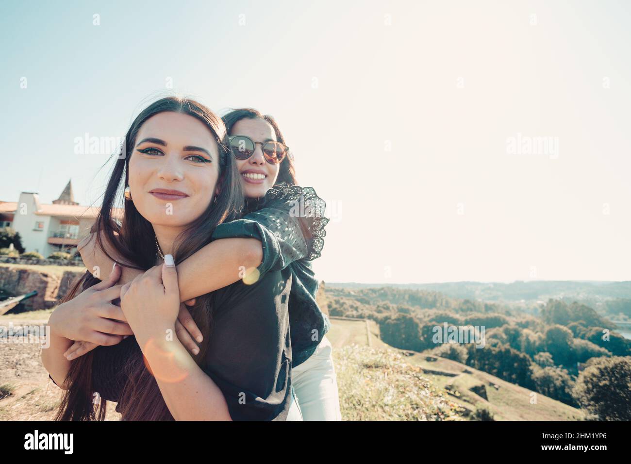 A front view of a couple of women smiling to camera while hugging each ...