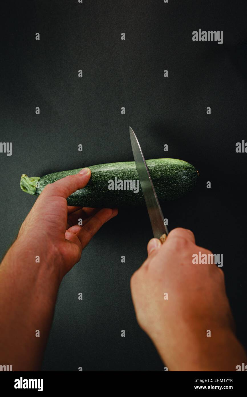 Two hands cutting a cucumber with a long knife Stock Photo - Alamy