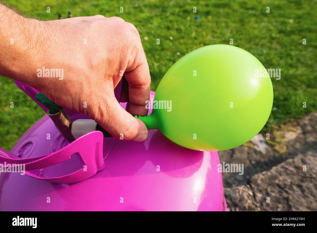 man filling green balloon with helium gas Stock Photo - Alamy
