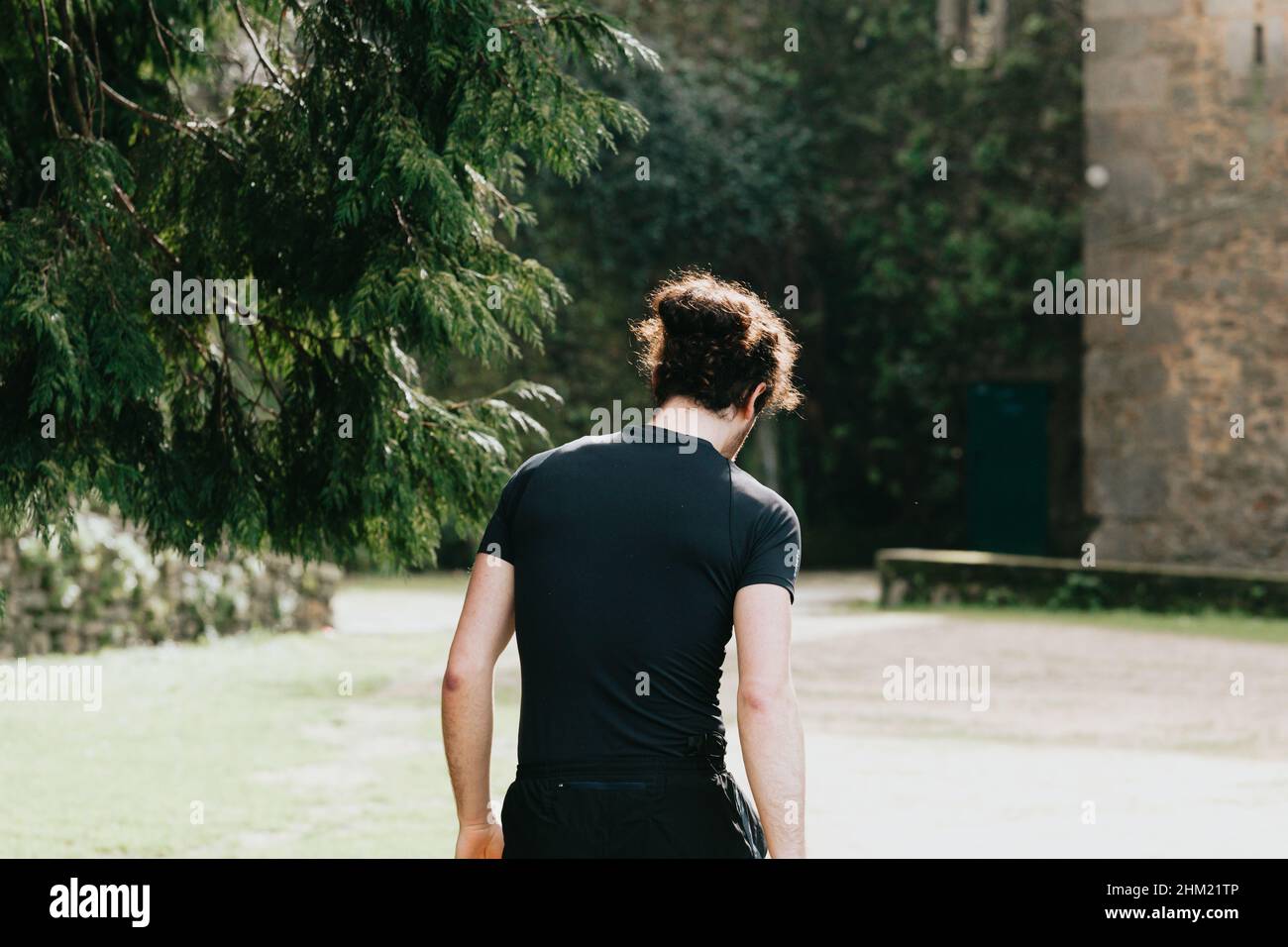 A close up of a long hair male running between the trees during a sunny ...