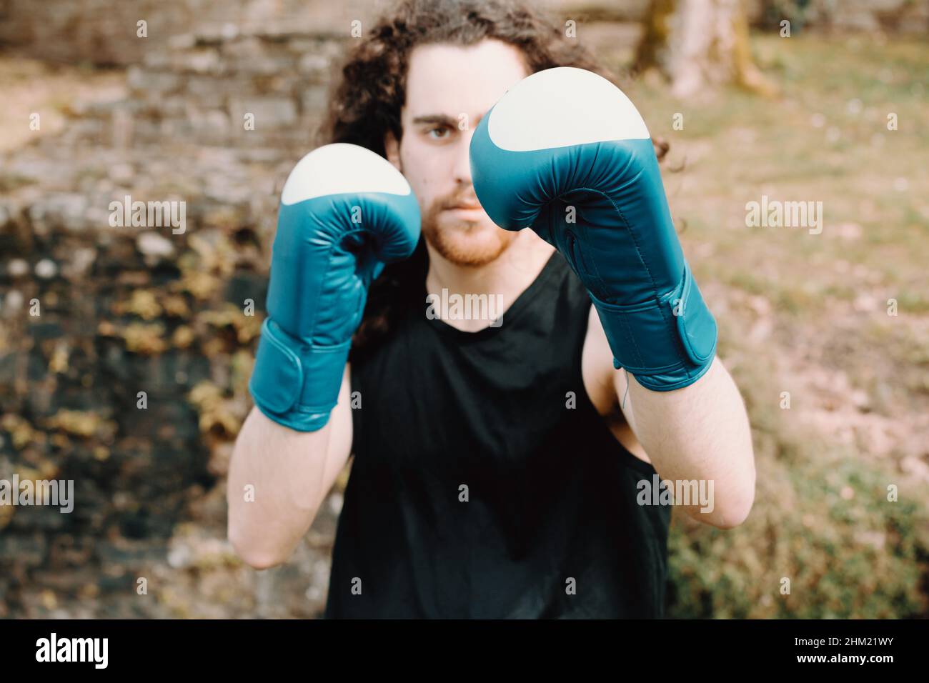 A young long hair man doing boxing and martial arts at the park with ...