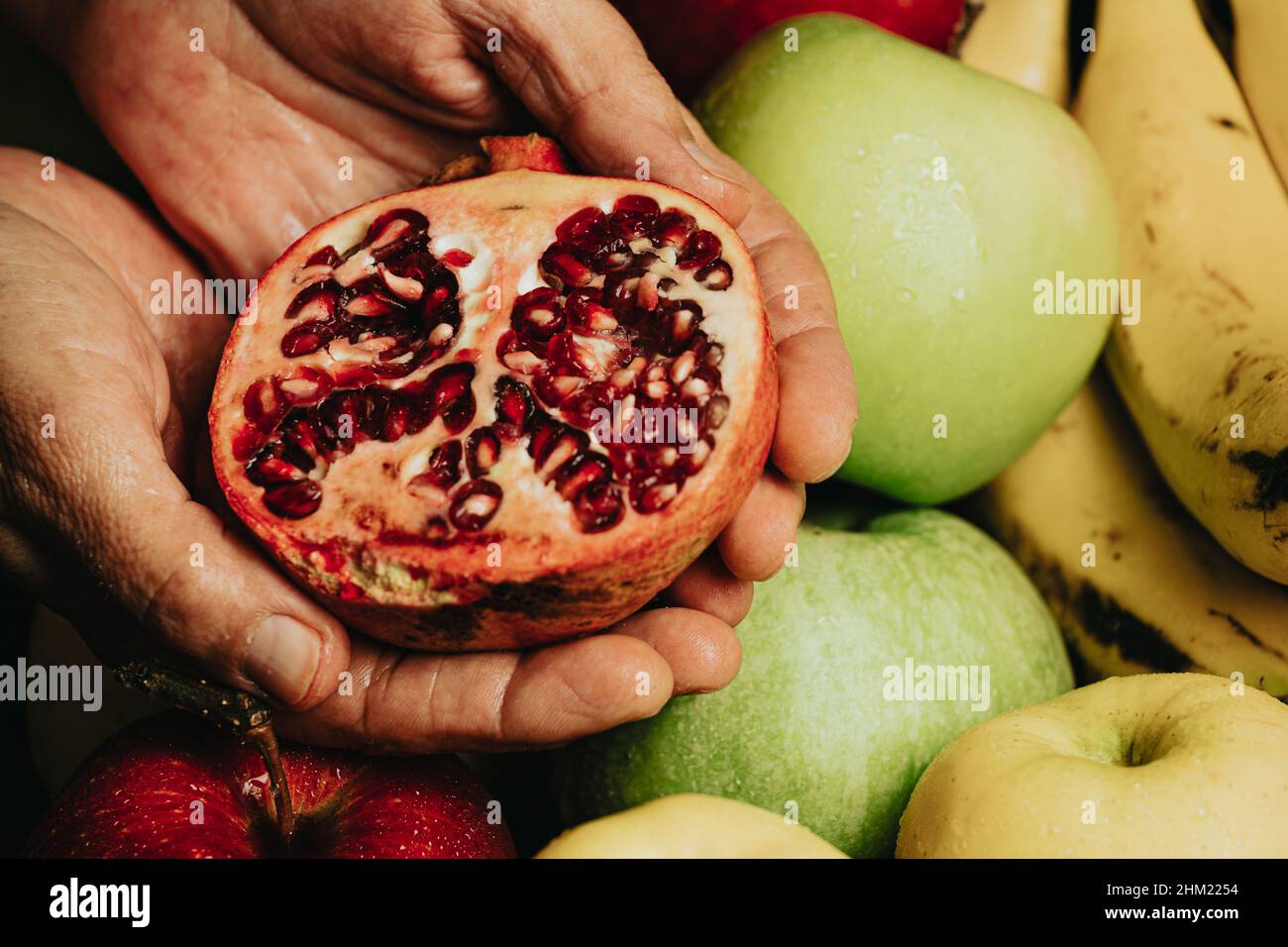 Old hands grabbing a passion fruit over a full of fruits background ...