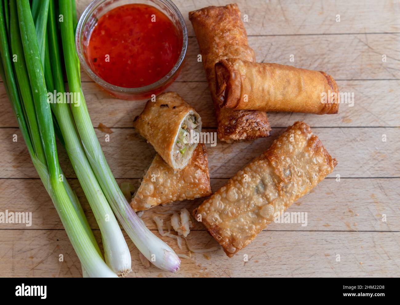 Crispy golden spring rolls on a wooden board with green onions and ...