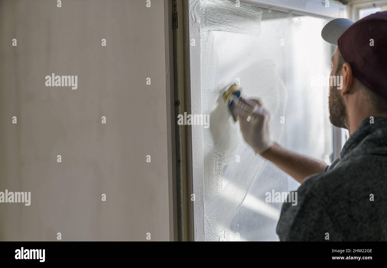 young man is using a sponge to clean a windows. professional window ...