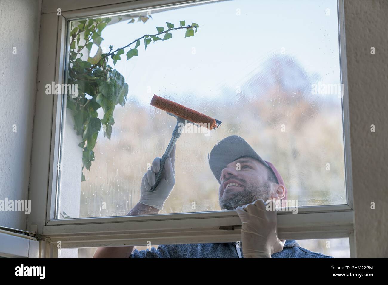 young man is using a rag and squeegee while cleaning windows ...