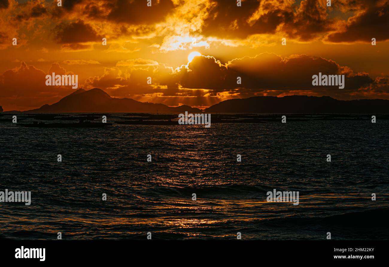 A massive sunset between the clouds with some islands over the ocean Stock Photo - Alamy