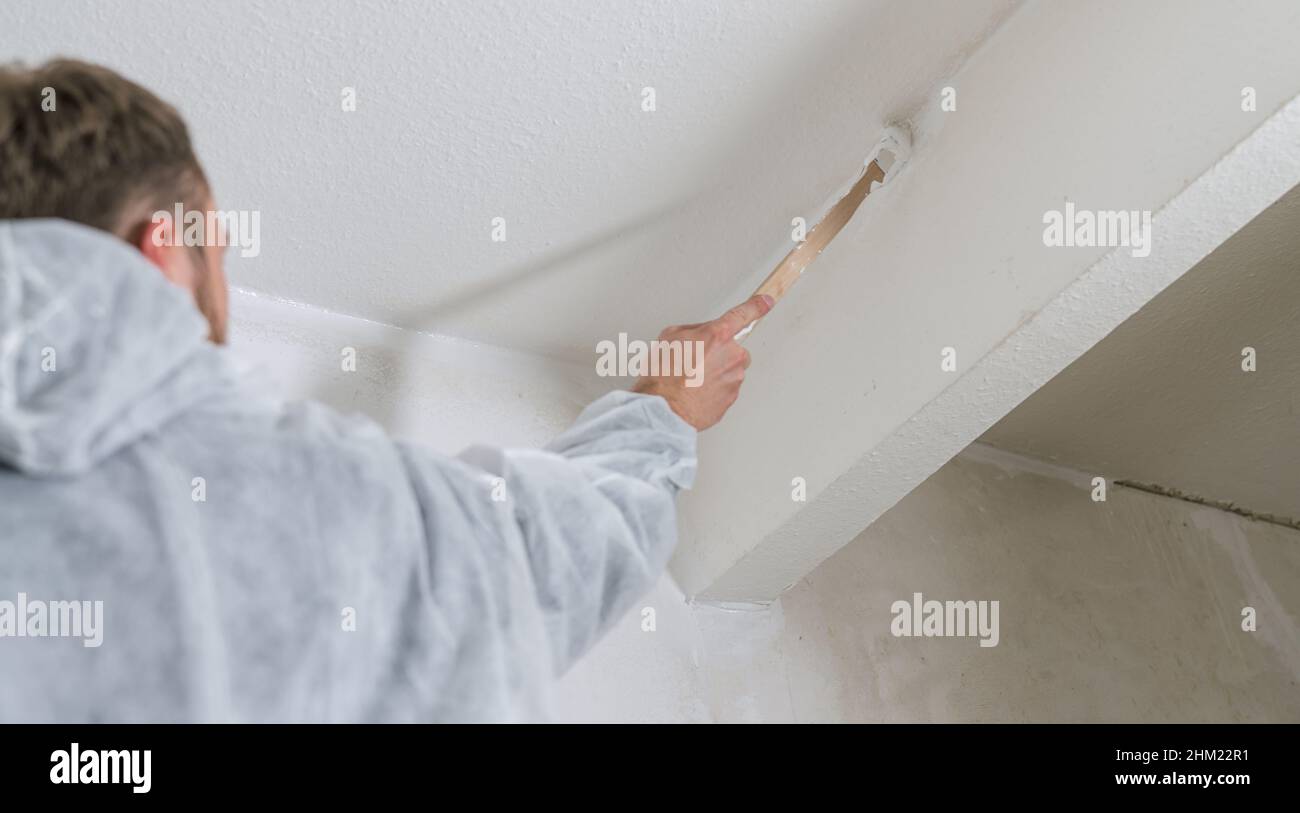 painter working with paint brush to paint the corner of a room with ...
