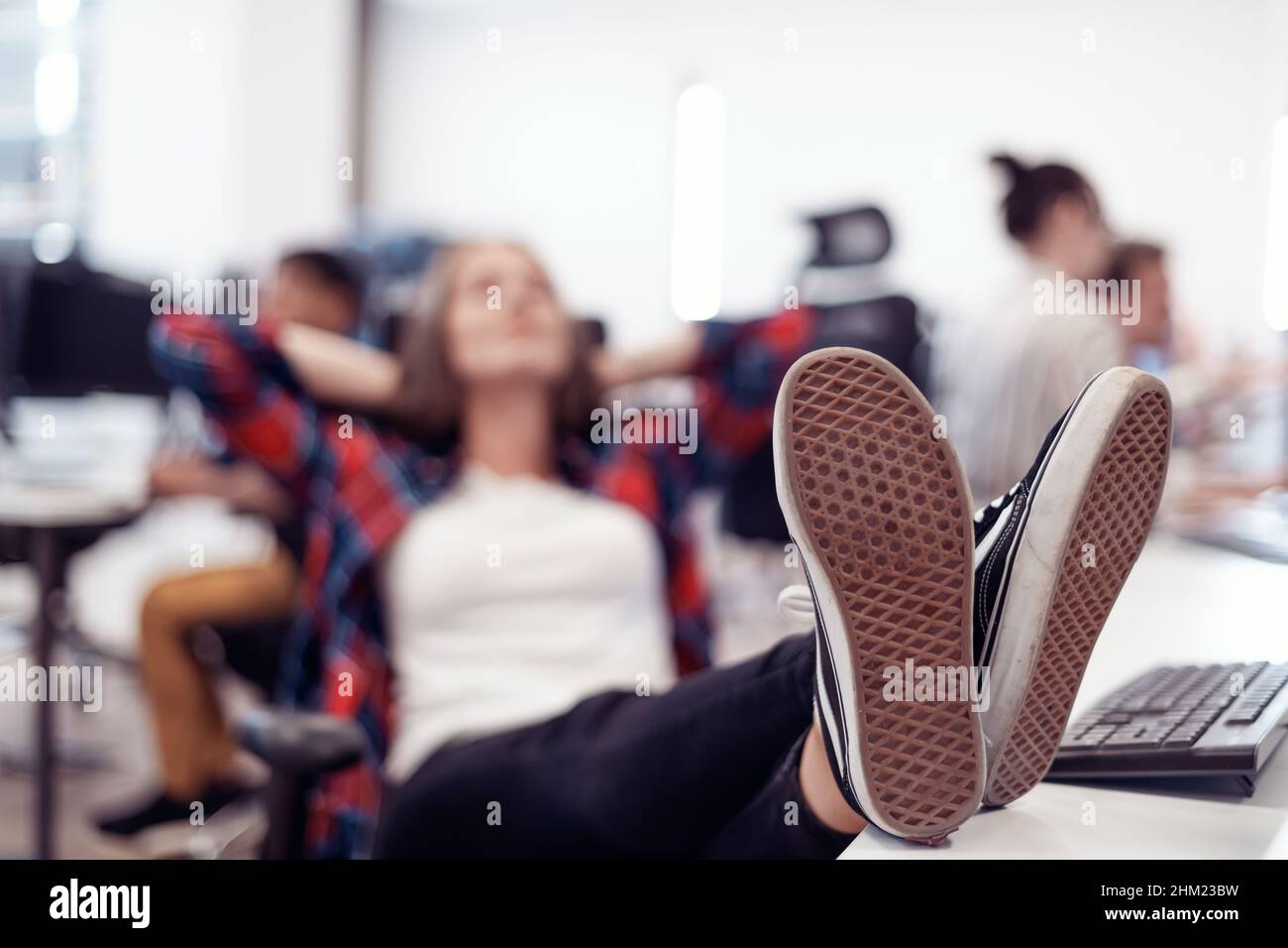 Casual business woman taking a break with legs on her table while ...