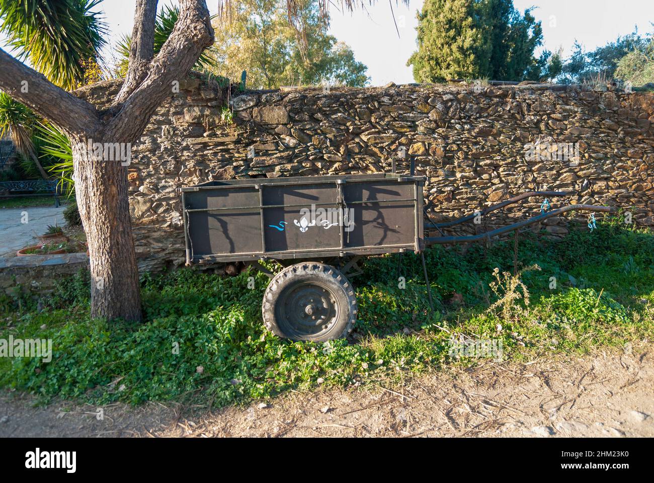 old, old and forgotten metal farm trailer next to stone wall Stock ...