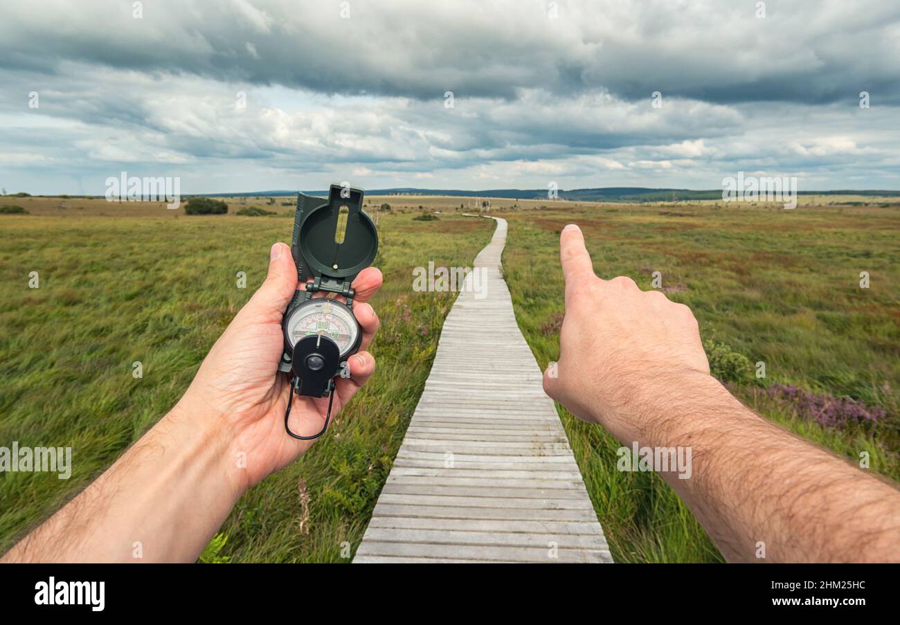 Male explorer searching direction with compass and shows the way in to ...
