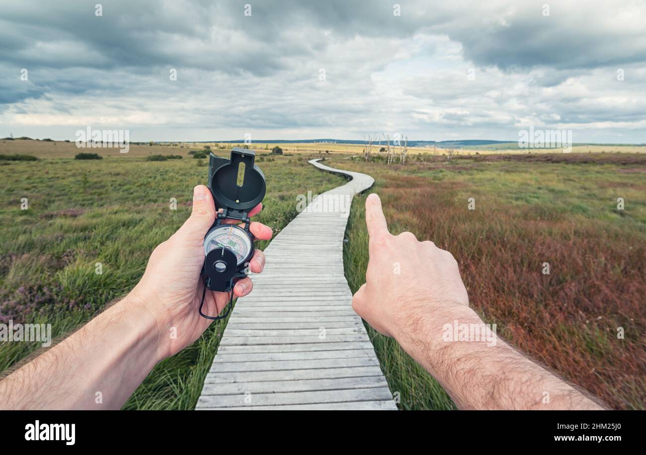 Traveler young man searching direction with a compass in the landscape ...