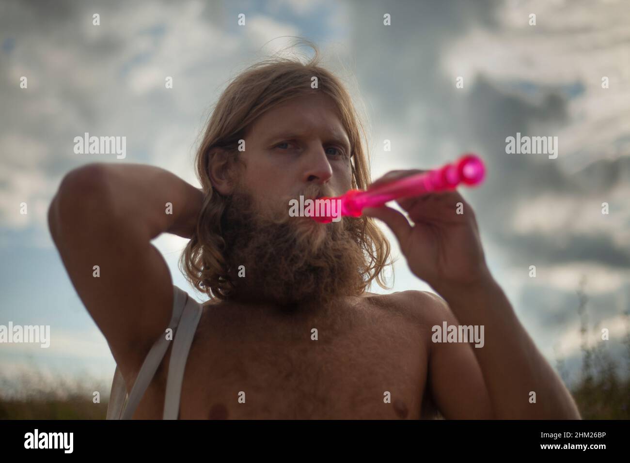 Guy plays flute. Man with long hair. Russian tourist. Traveler extracts ...