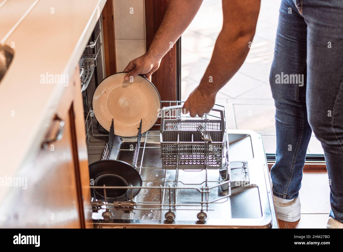 a man putting a dirty plate in the dishwasher Stock Photo - Alamy