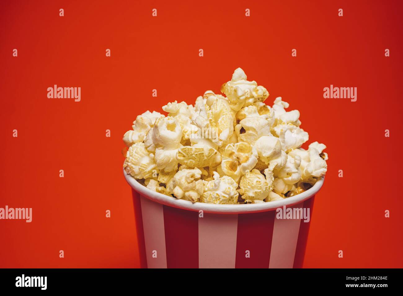 Popcorn in a round box and around on a bright red background Stock ...