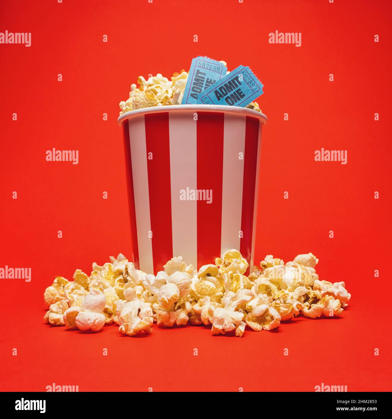shot of a round popcorn box with two blue tickets on a red background ...